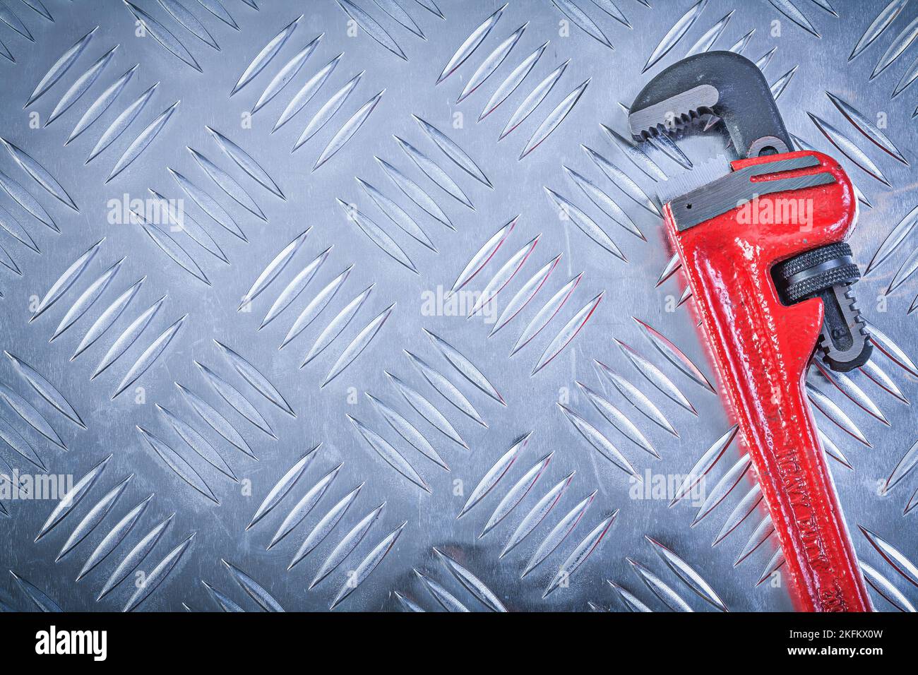 Adjustable monkey wrench on channeled metal sheet copy space ...