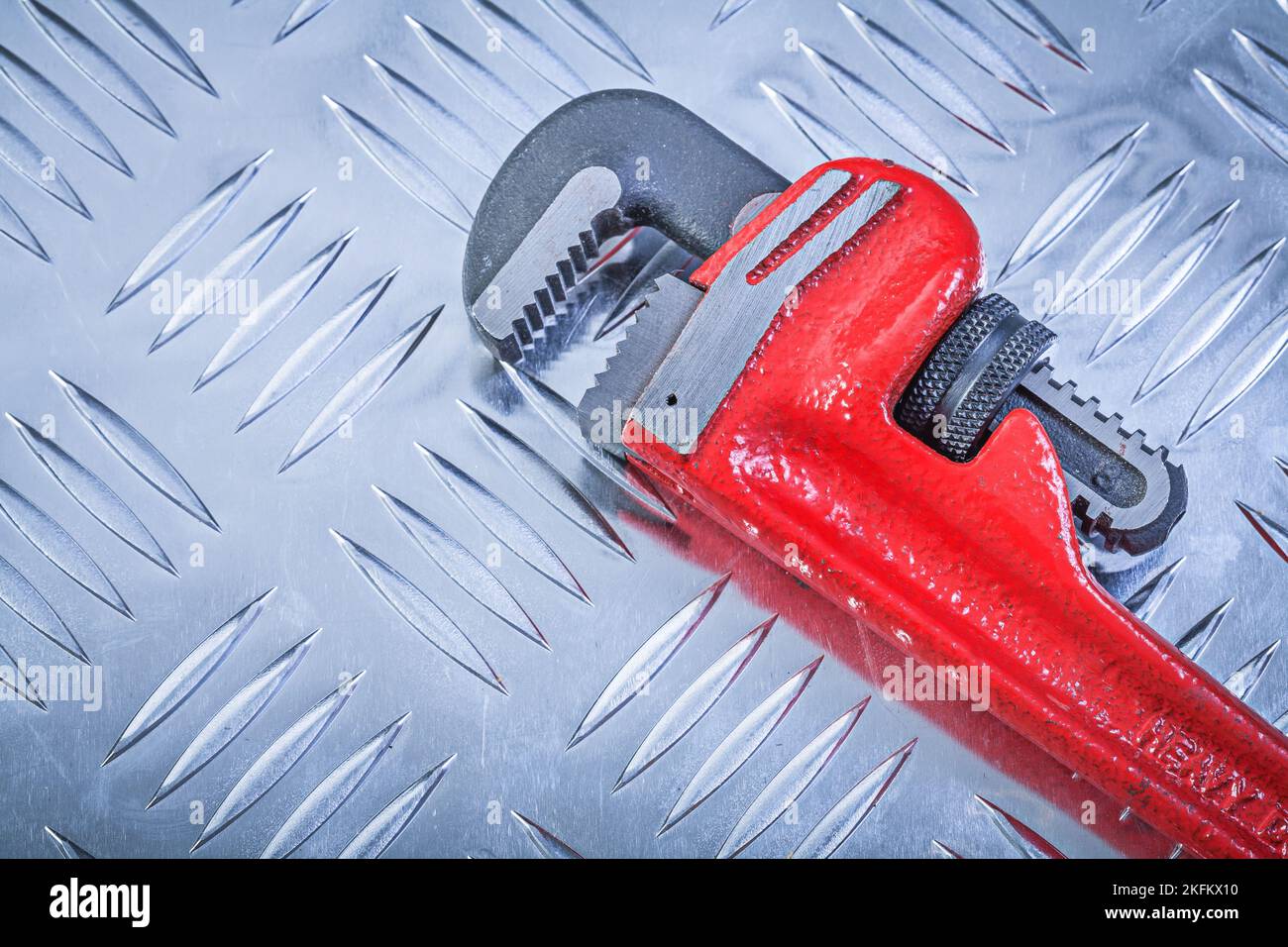 Adjustable monkey wrench on fluted metal plate construction concept ...