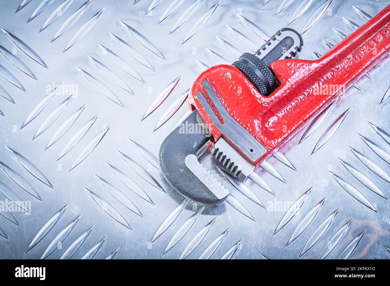 Adjustable monkey wrench on grooved metal background construction ...