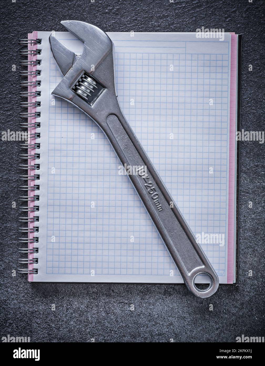 Adjustable spanner notebook on black background construction concept ...