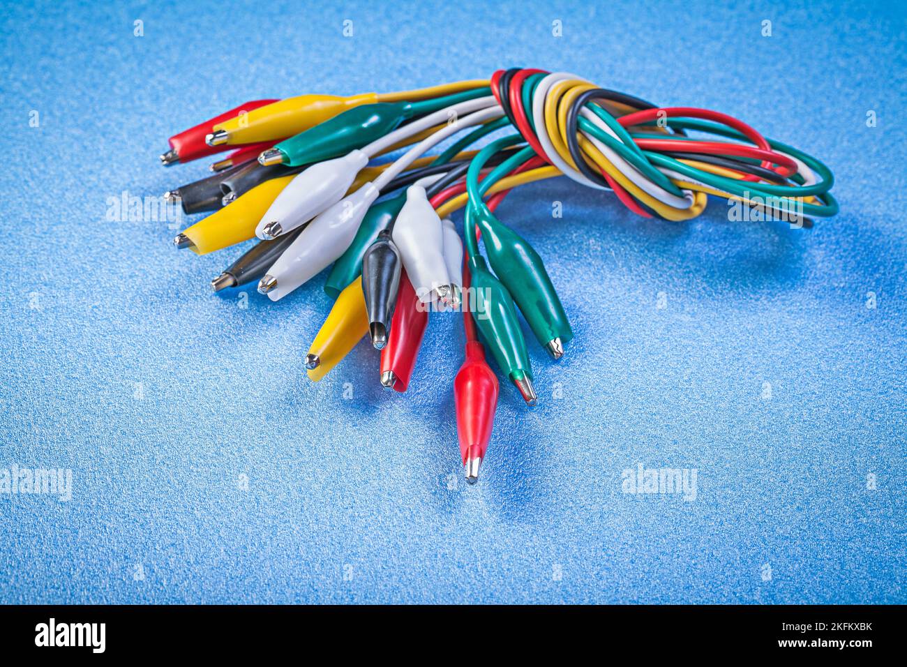 Assortment of multicolored crocodile clip cables on blue background ...