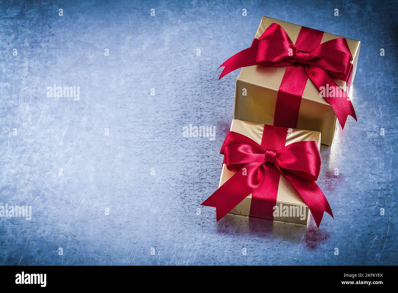 Boxed golden presents with red bow on scratched metallic background ...