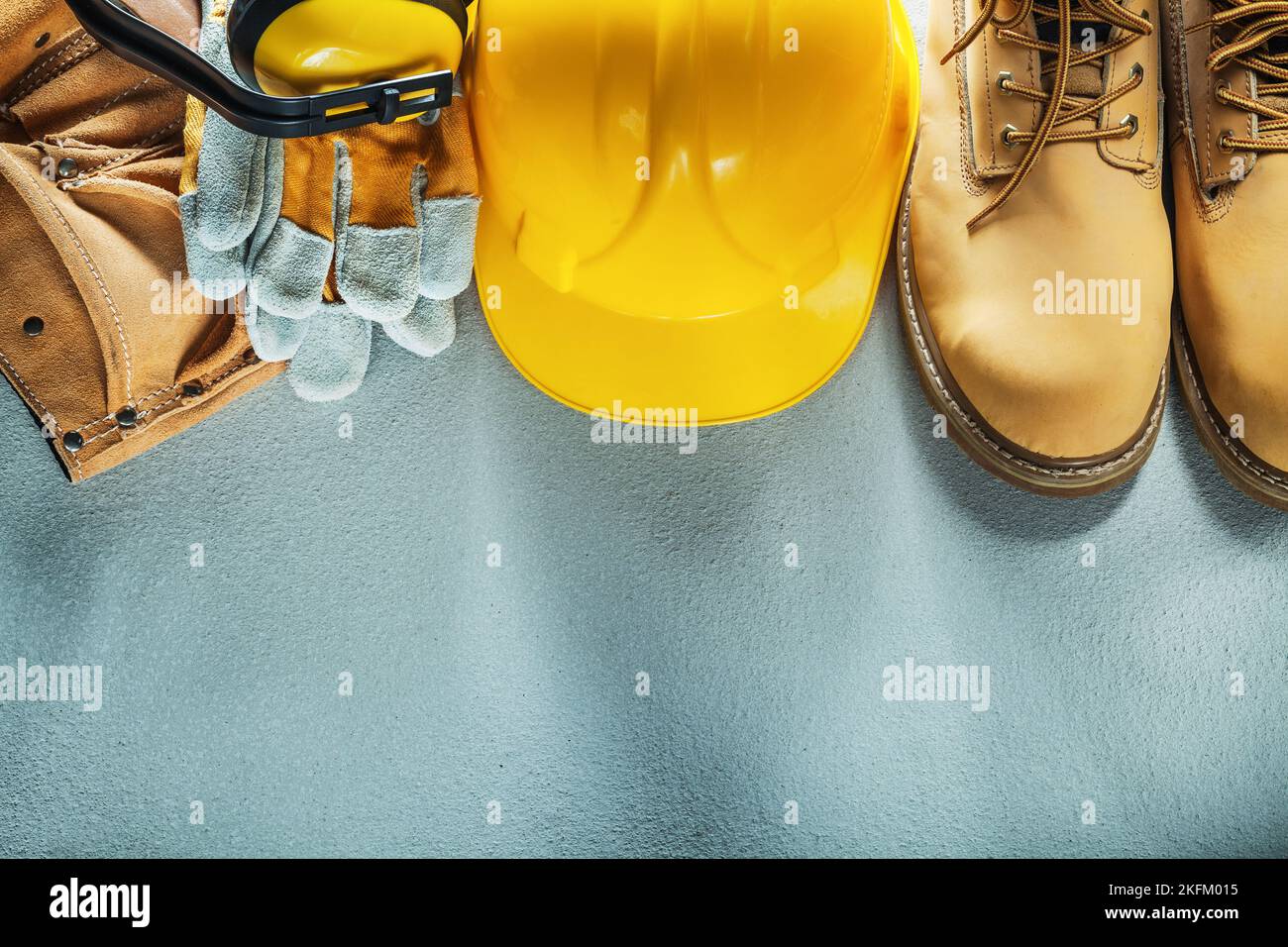 Building helmet tool belt safety gloves boots earmuffs on concrete ...