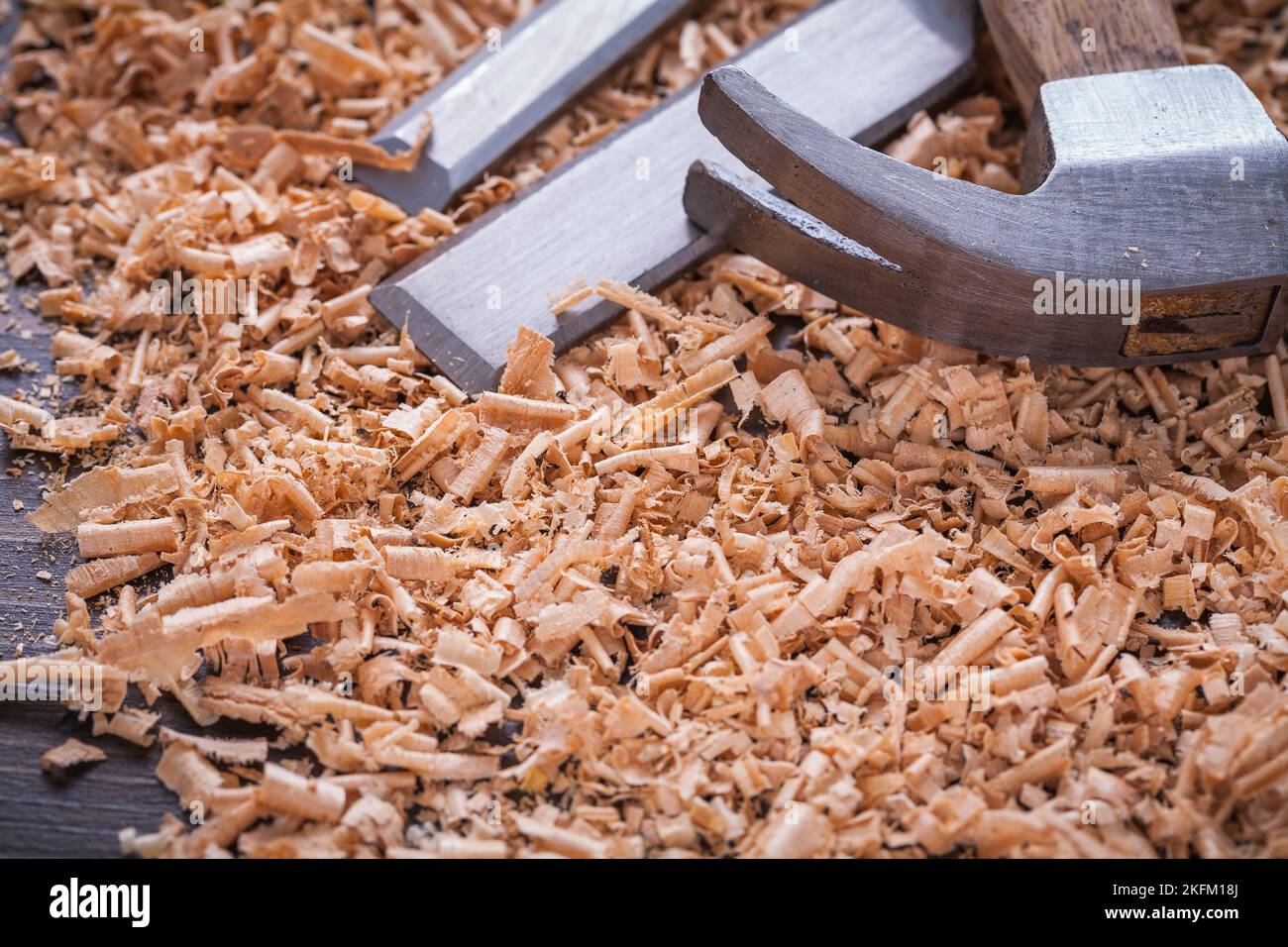 Close up view of claw hammer and metal chisels in wooden planning chips ...