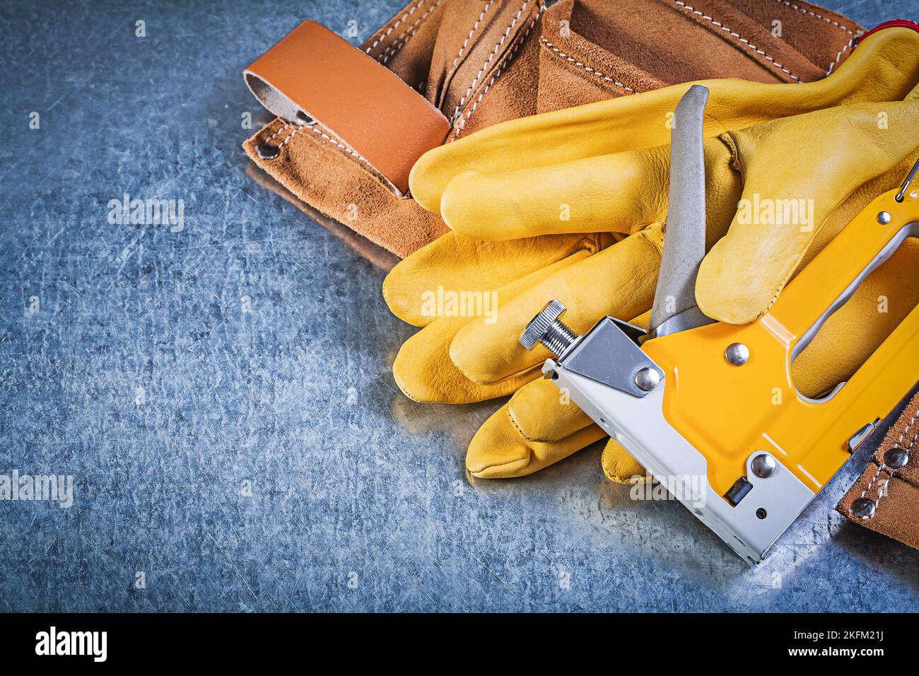 Composition of leather tool belt safety gloves stapler gun on metallic ...