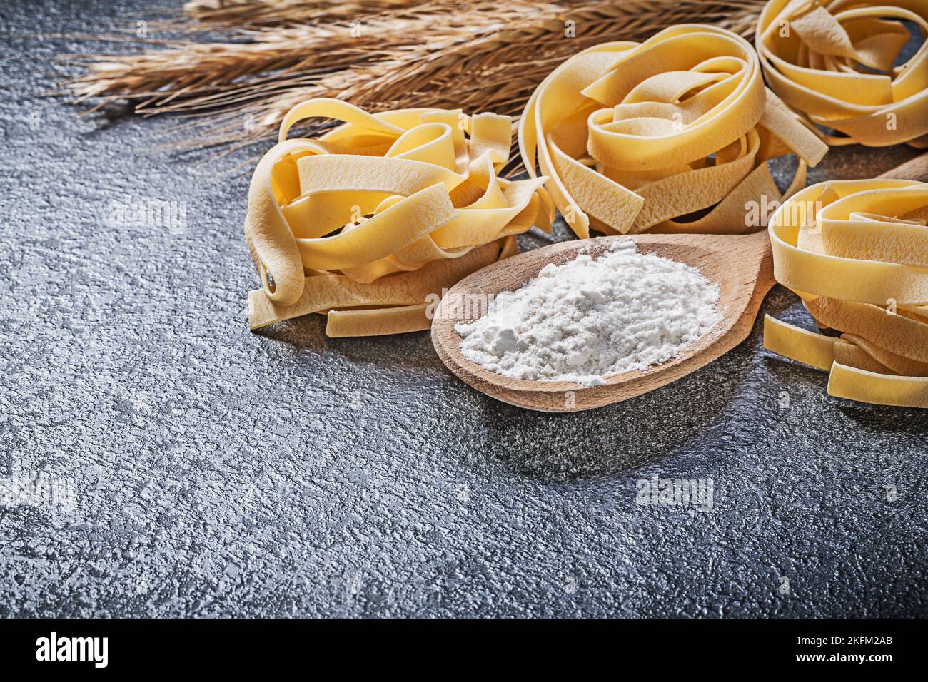 Composition of wheat rye ears wooden spoon flour pasta fettuccine on ...