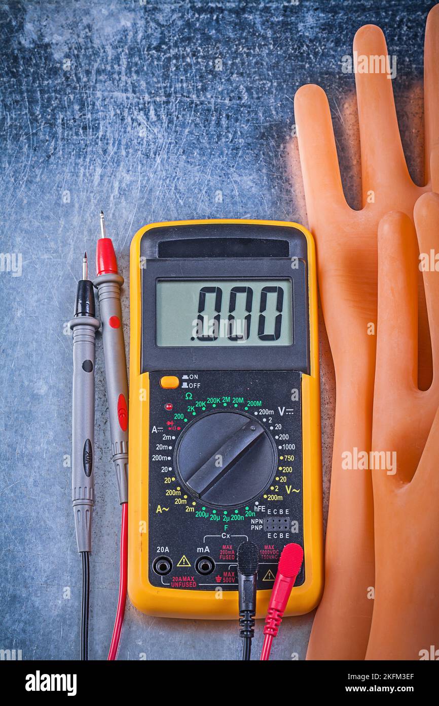 Digital multimeter dielectric rubber gloves on metallic background ...