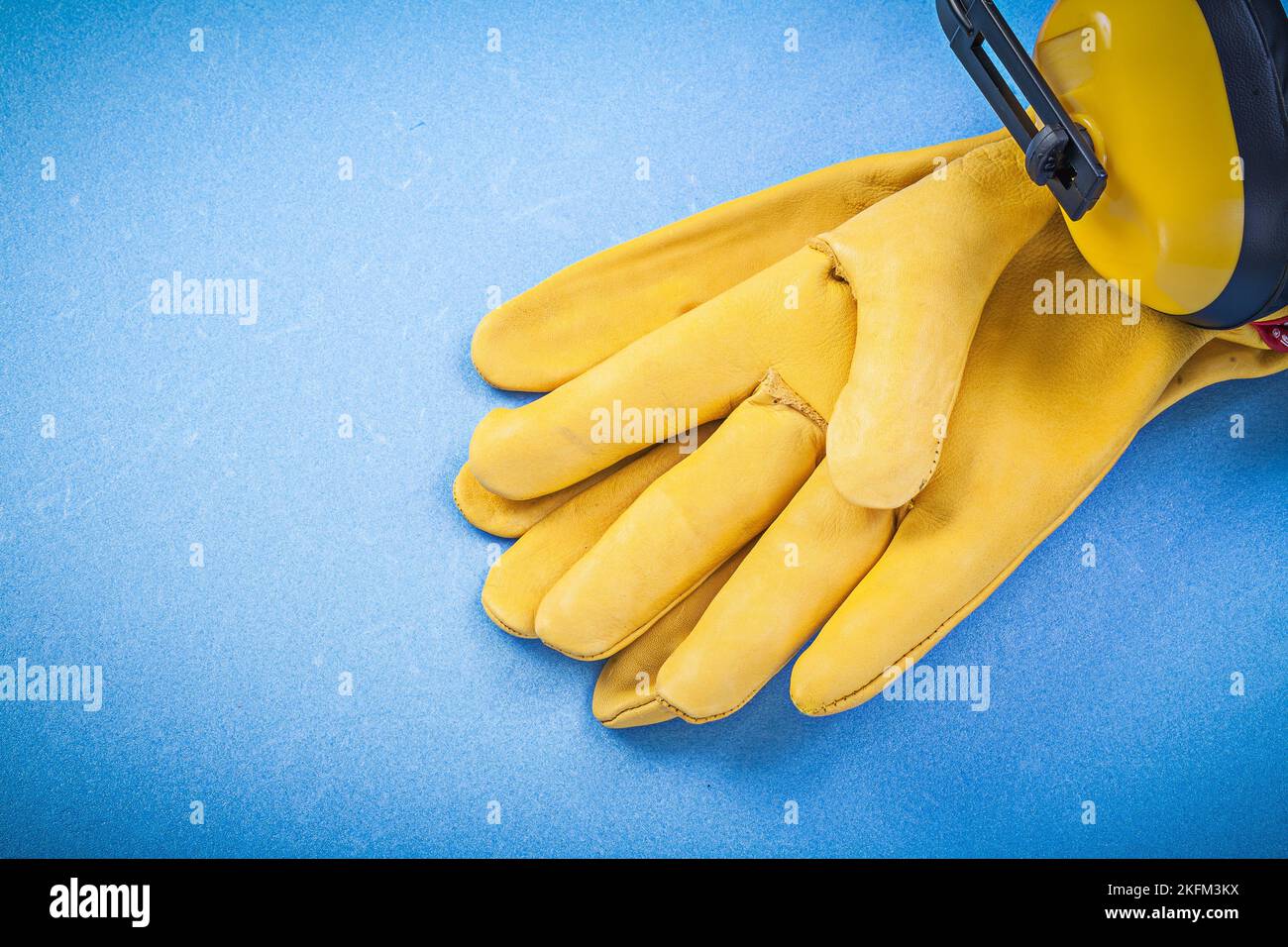 Earmuffs leather safety gloves on blue background construction concept ...