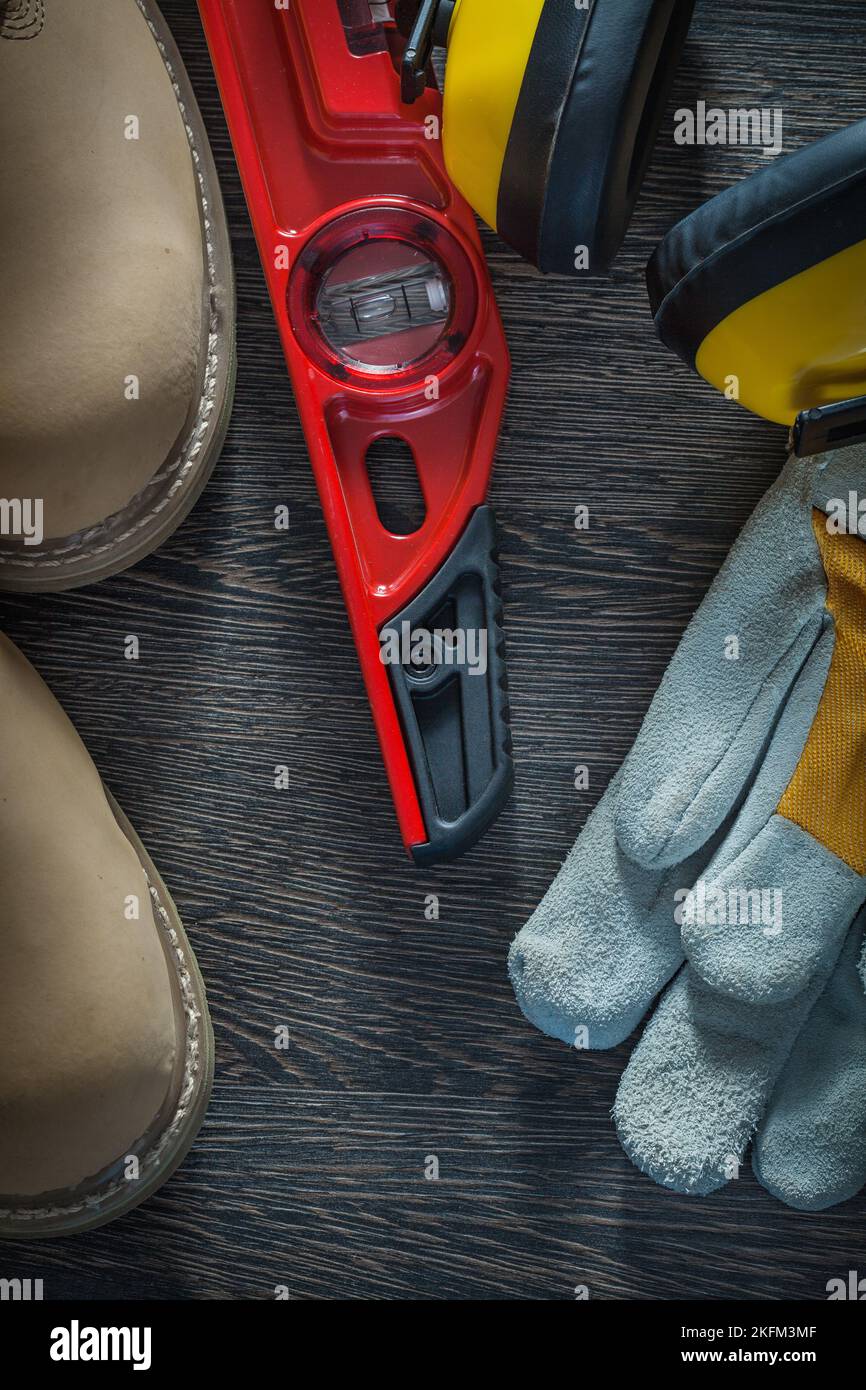 Earmuffs safety gloves waterproof boots construction level on wooden ...