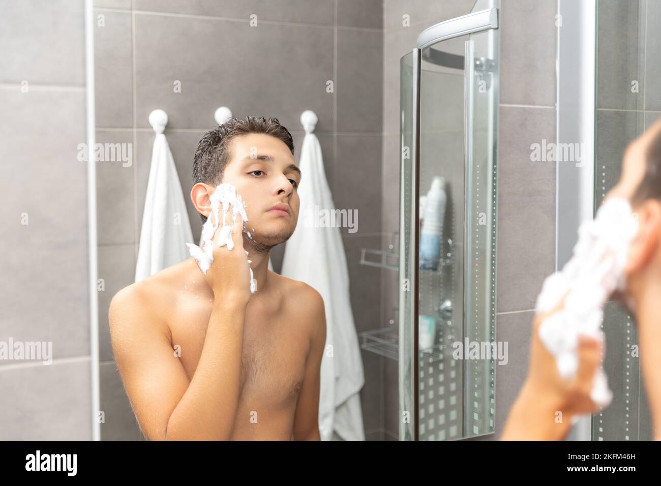 The young man shaving process in bathroom. The teenager shave off the ...