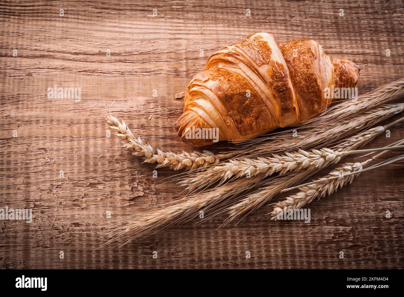 Fresh-baked croissant heap of wheat ears on oak wooden board food and ...