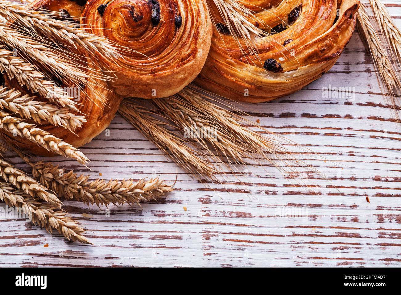 Fresh-baked buns with raisins golden wheat ears on vintage wooden board ...