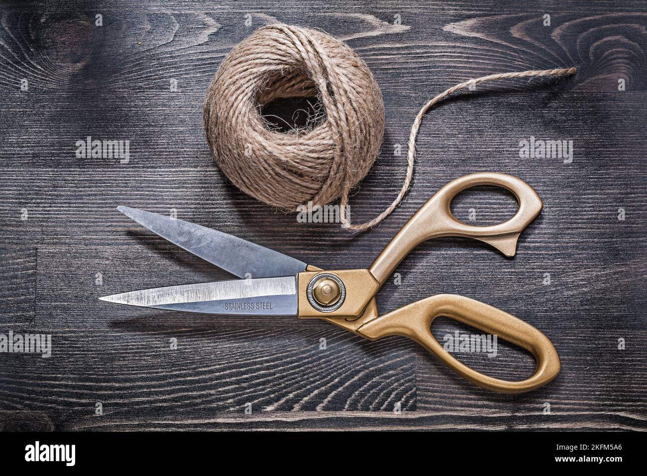 Golden scissors hank of rope on vintage wooden board Stock Photo - Alamy