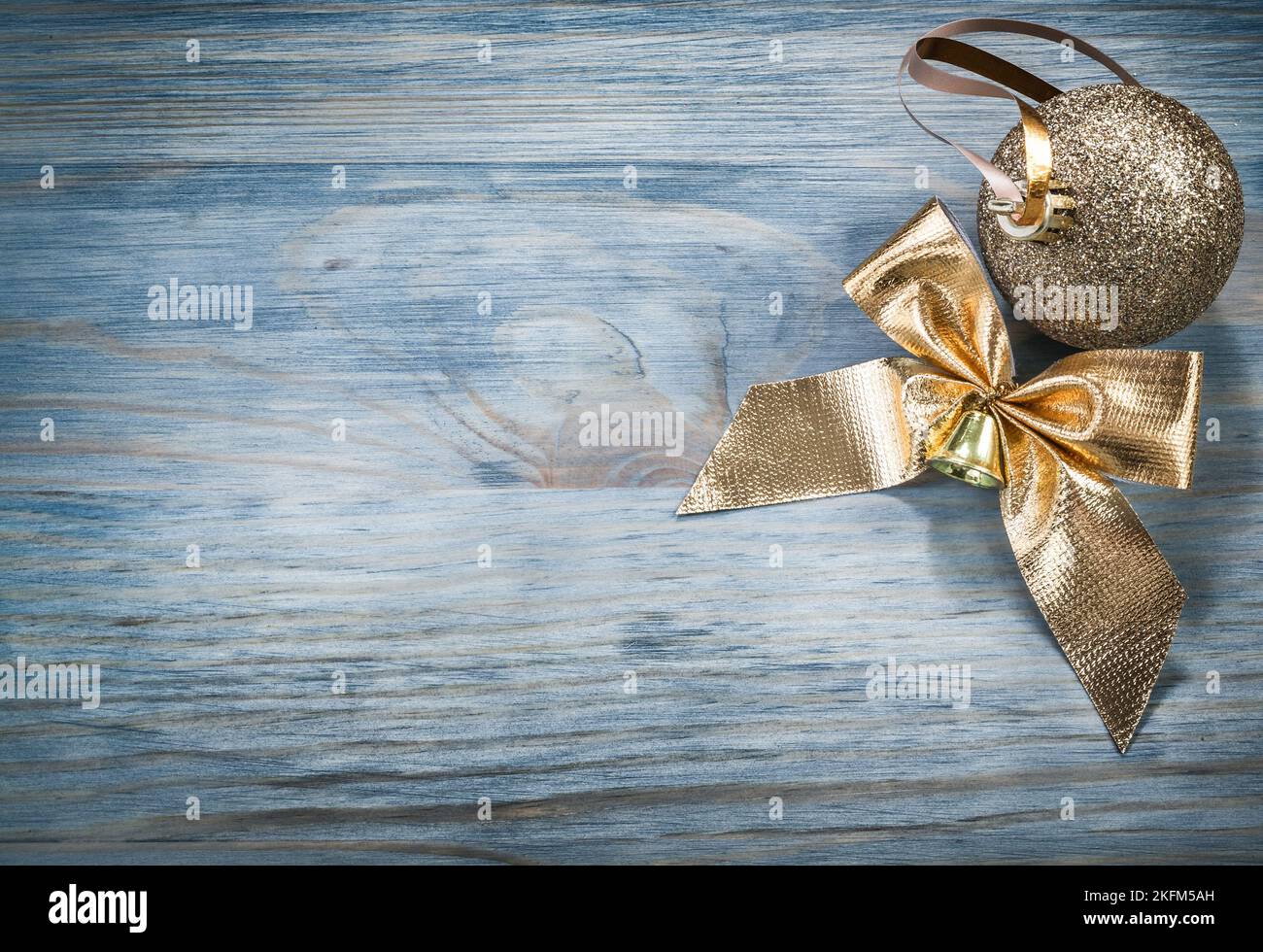 Goldish shiny Christmas ball bow on wooden board copy space holidays ...