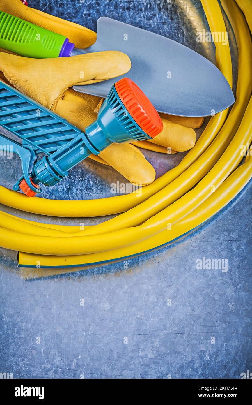 Hand spraying garden hose safety gloves spade on metallic background ...