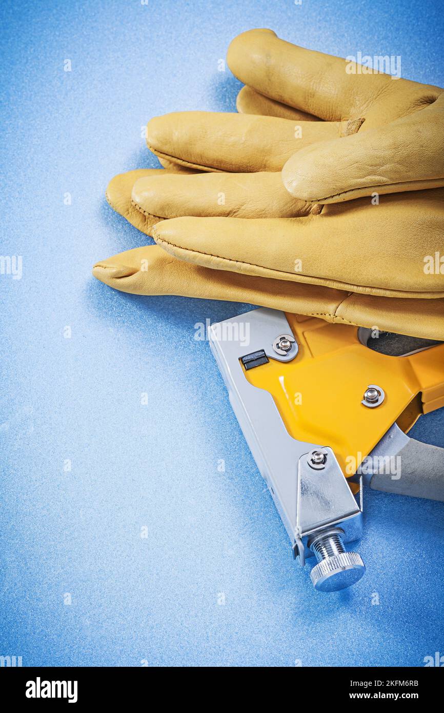 Leather protective gloves yellow construction stapler on blue ...