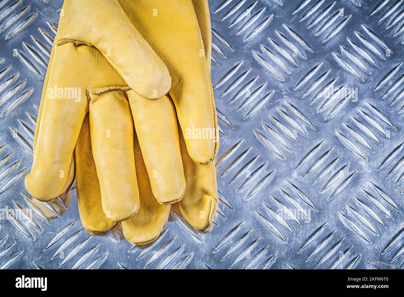 Leather protective gloves on fluted metal sheet construction concept ...