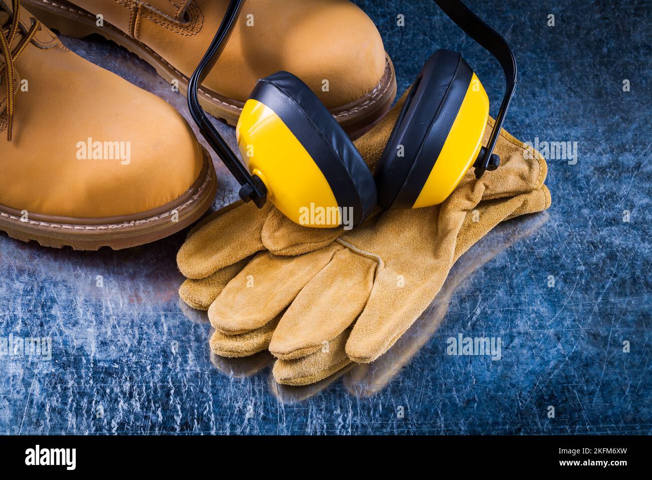 Leather safety boots gloves and noise insulation ear muffs on scratched ...