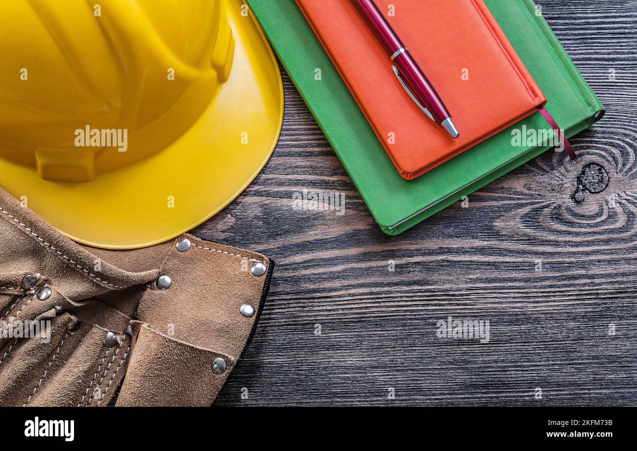 Leather tool belt notepads pen protective hard hat on wooden board ...