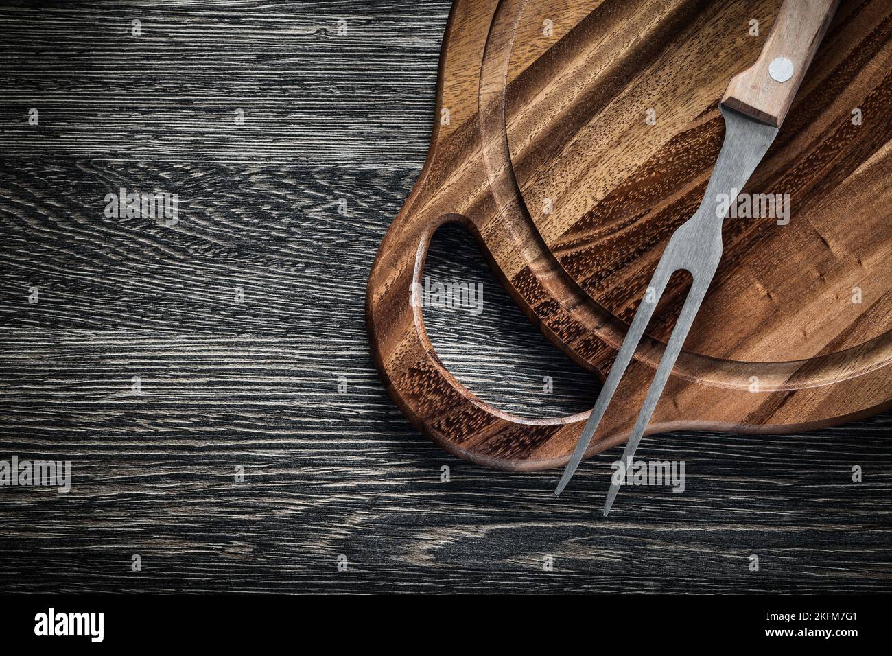 Meat fork chopping board on wood background Stock Photo - Alamy