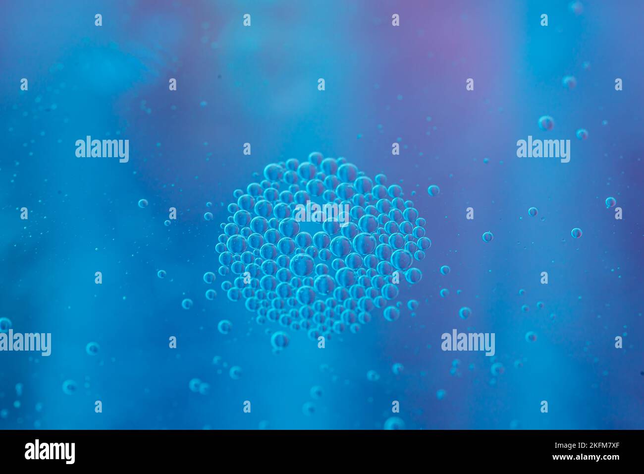 small drops of oil in water on blue background. macro photo Stock Photo ...
