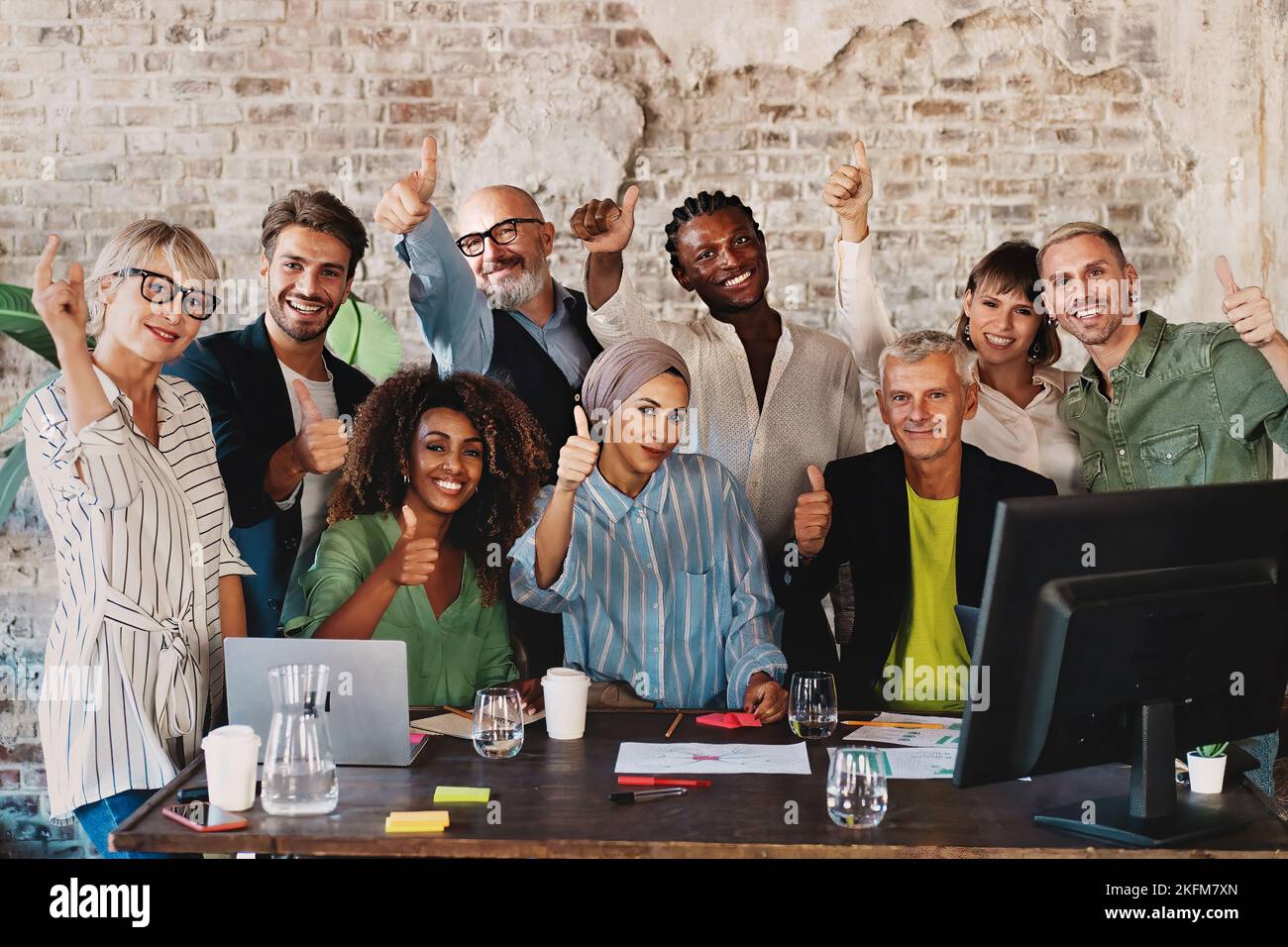 Multi-ethnic group of coworkers in thumbs-up pose sitting at office ...