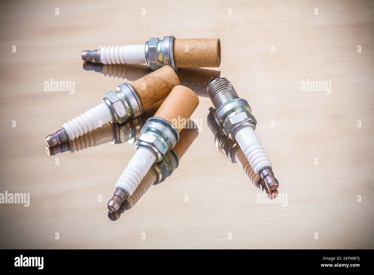 old sparks plugs on light brown background Stock Photo - Alamy