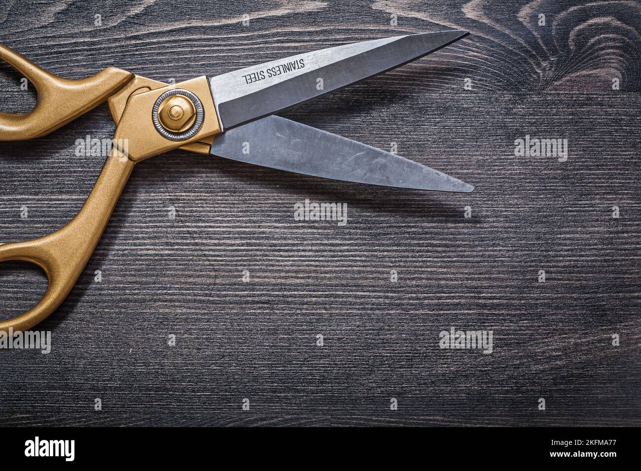 Pair of golden scissors on vintage wooden board top view Stock Photo ...