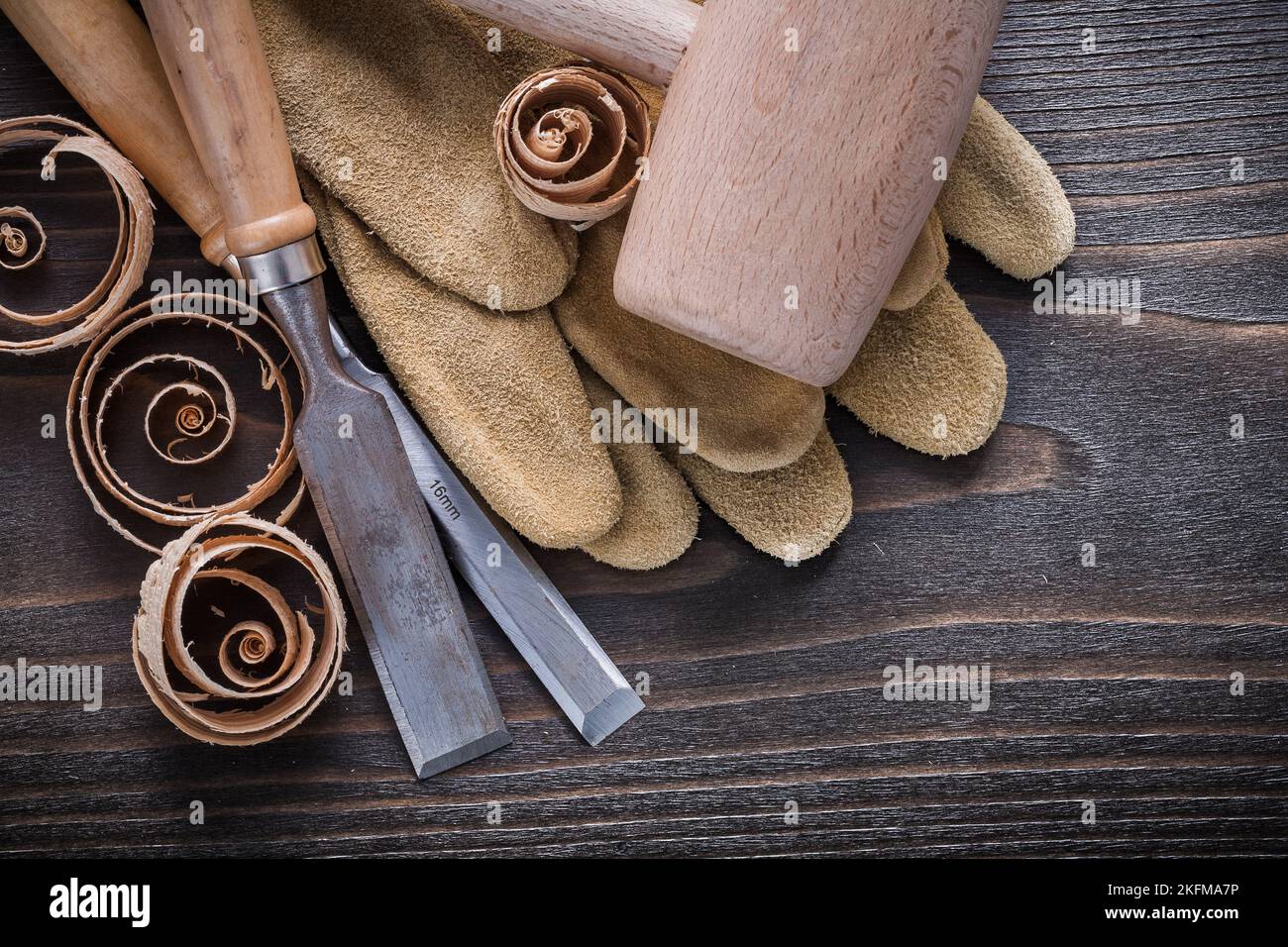 Pair of brown leather gloves firmer chisels wooden mallet and curled up ...