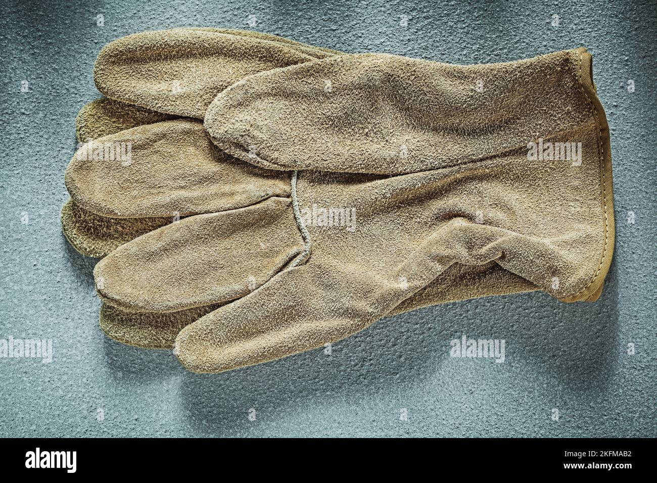 Pair of leather safety gloves on concrete surface construction concept ...