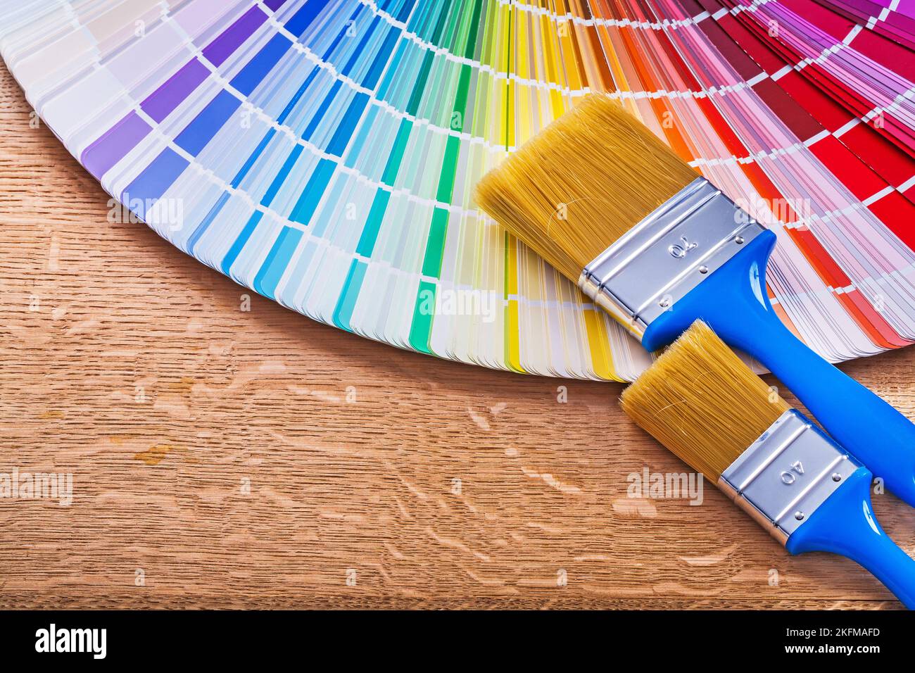 Pantone color palette guide and paint brushes on wooden board ...