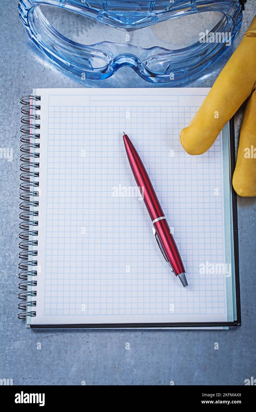 Plastic goggles protective gloves copybook pen on metallic background ...
