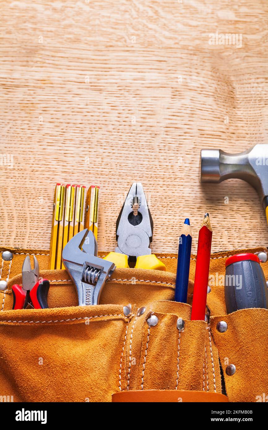 pliers nippers wrench pencil hammer in tool belt on wooden board Stock ...