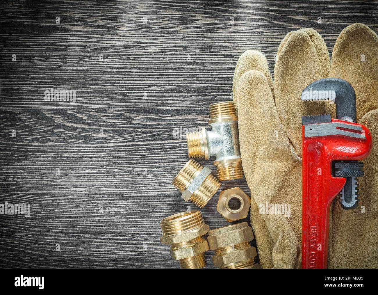 Plumbing pipe wrench fittings safety gloves on wooden board Stock Photo ...