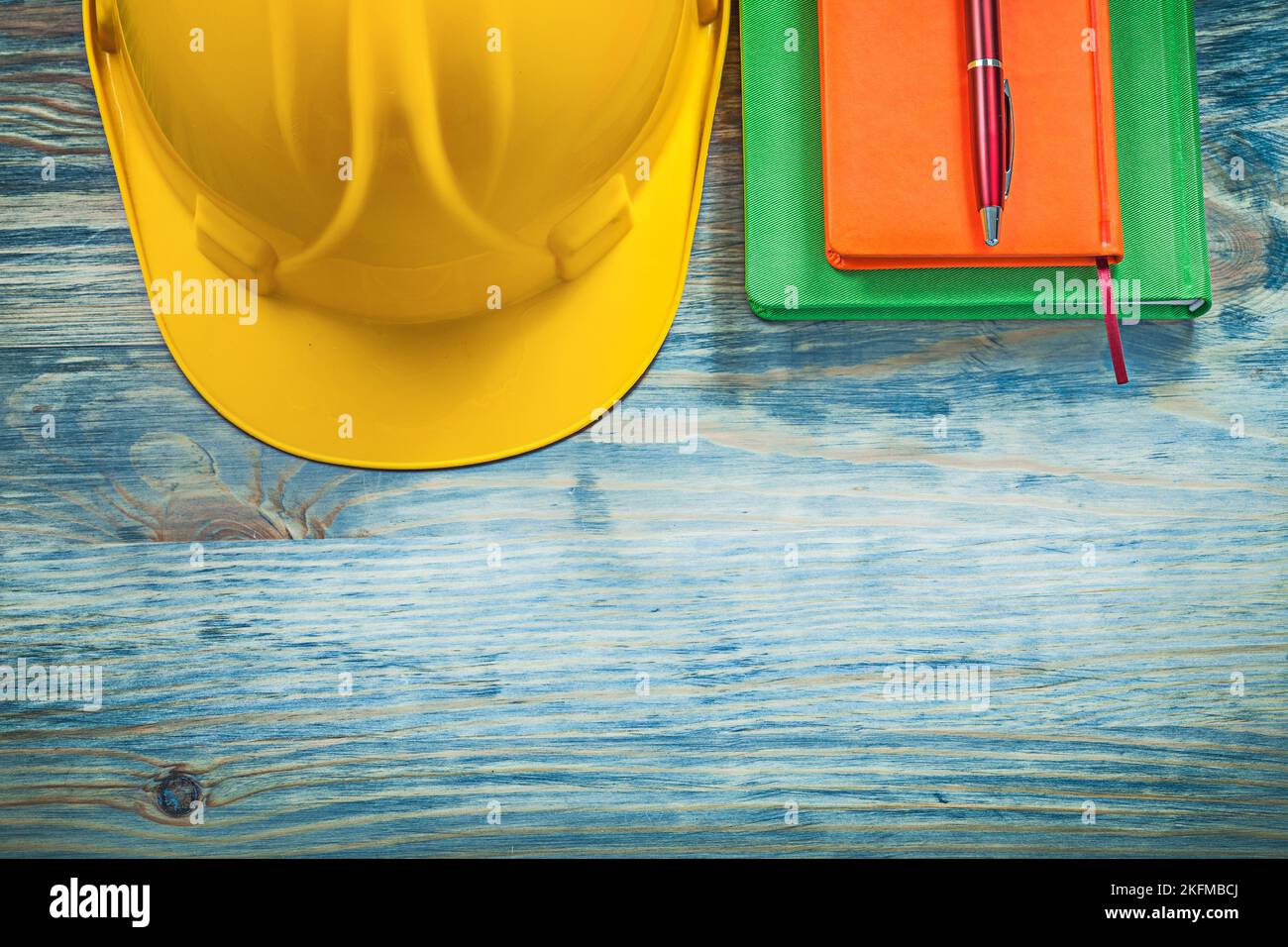Protective building helmet notepads ballpoint pen on wood board ...