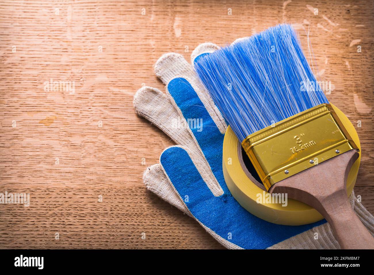Protective gloves paint brush and duct tape on wooden board ...