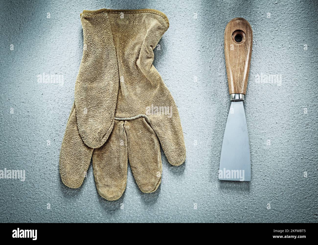 Putty knife safety gloves on concrete background construction concept ...