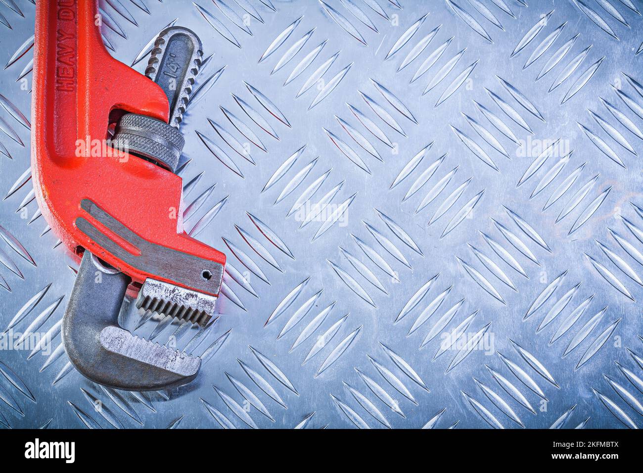 Red adjustable monkey wrench on corrugated metallic sheet copyspace ...