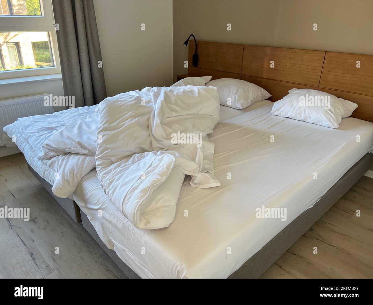 bed, a messy double bed with white bedding sets in a bedroom of a house ...