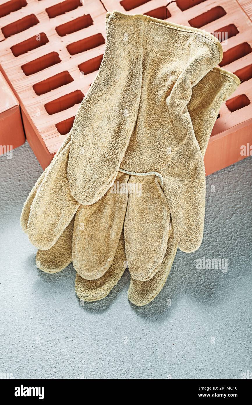 Red bricks safety gloves on concrete background construction concept ...
