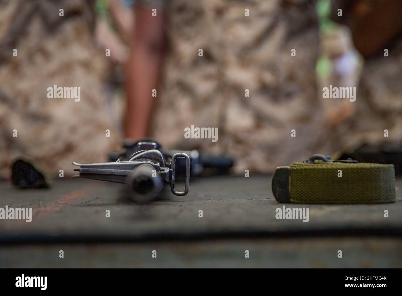 An M16A4 service rifle, sling, and cleaning kit lay on a table in front ...