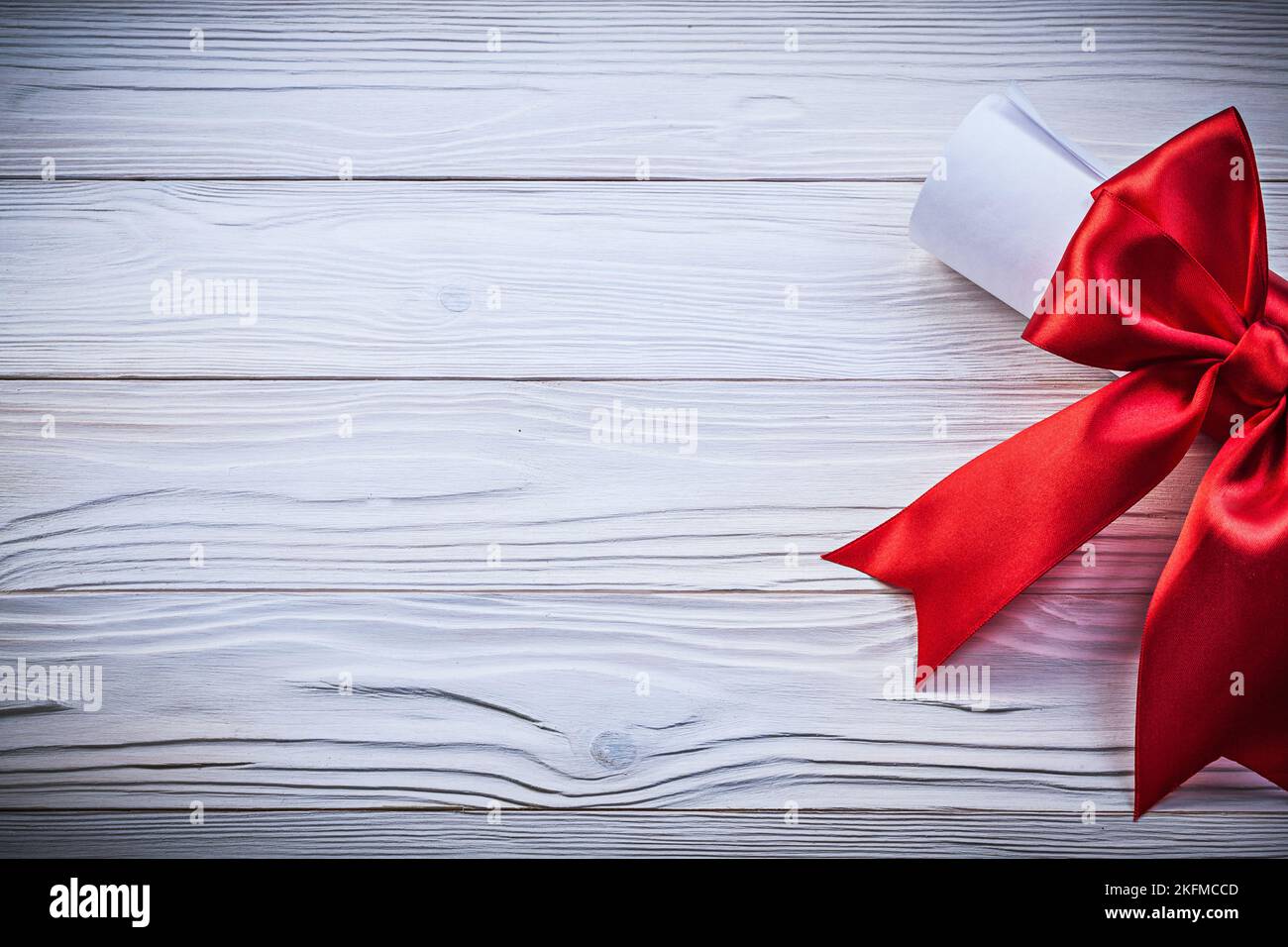 Roll of paper with red satin ribbon on wooden board holidays concept ...