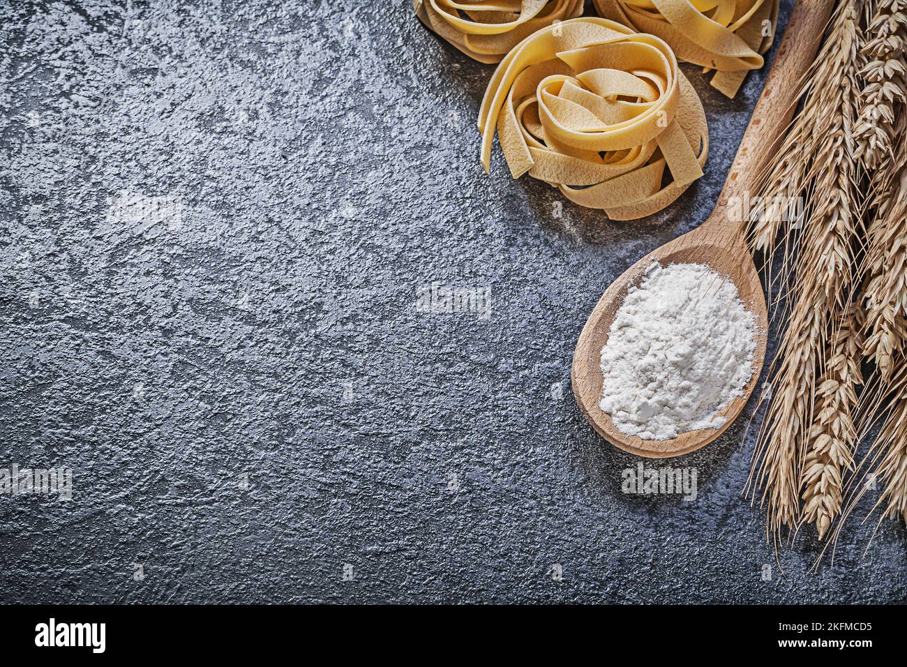 Ripe wheat rye ears wooden spoon flour raw spiral macaroni on black ...