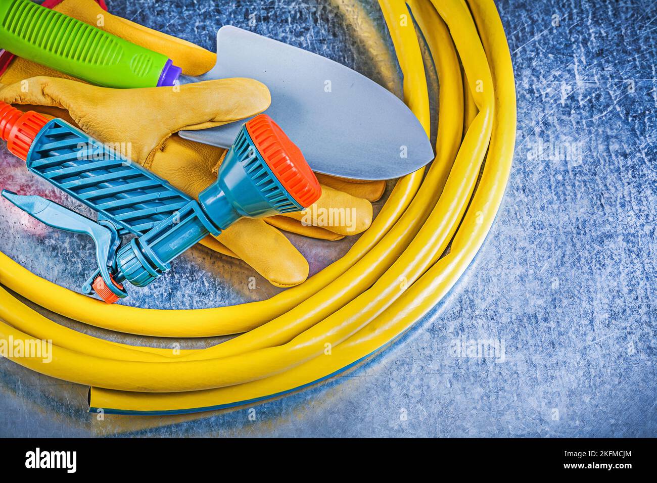 Rubber garden hose spray nozzle safety gloves hand spade on metallic ...