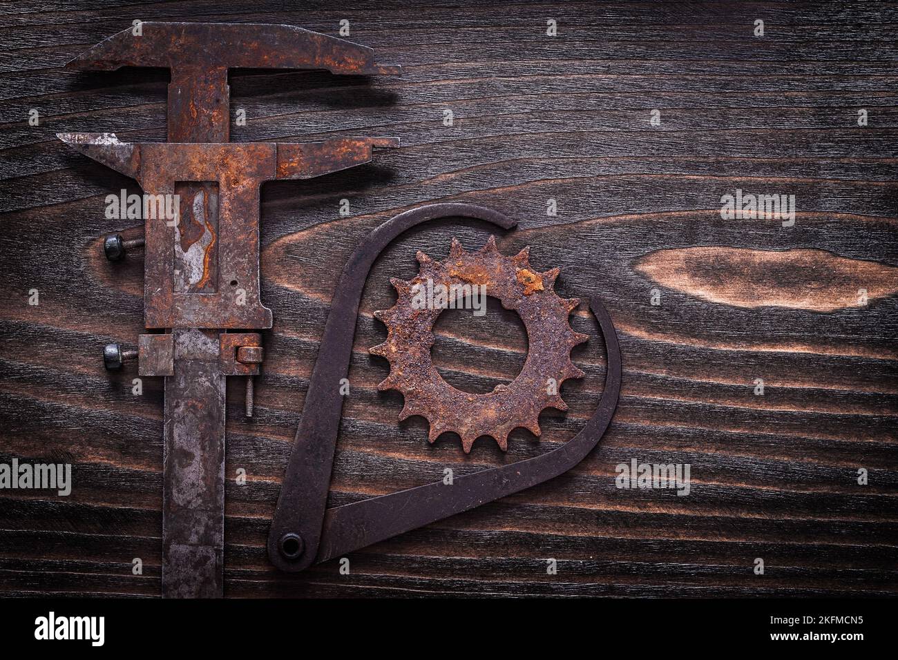 Rusted obsolete measuring calipers and cog-wheel on vintage wooden ...
