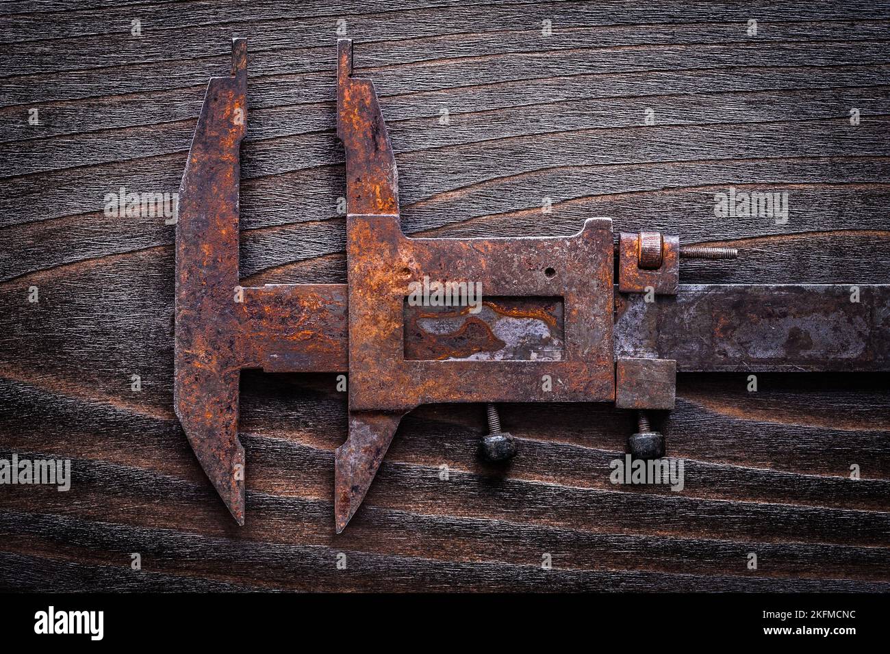 Rusted old-fashioned measuring slide caliper on vintage wooden board ...