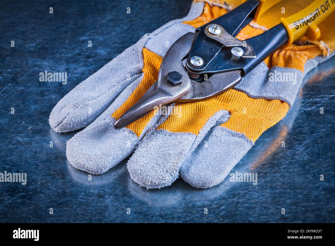 Safety gloves with tin snips on scratched vintage metallic background ...