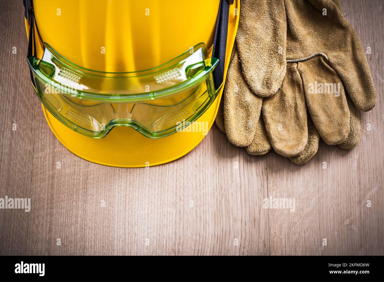 Safety leather gloves hard hat and plastic glasses on wooden board ...