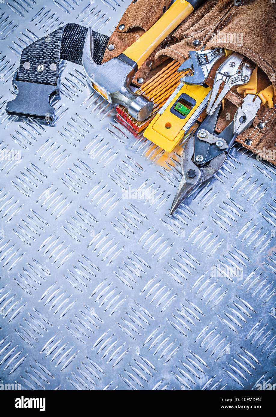 Set of construction tooling in toolbelt on channeled metal background ...