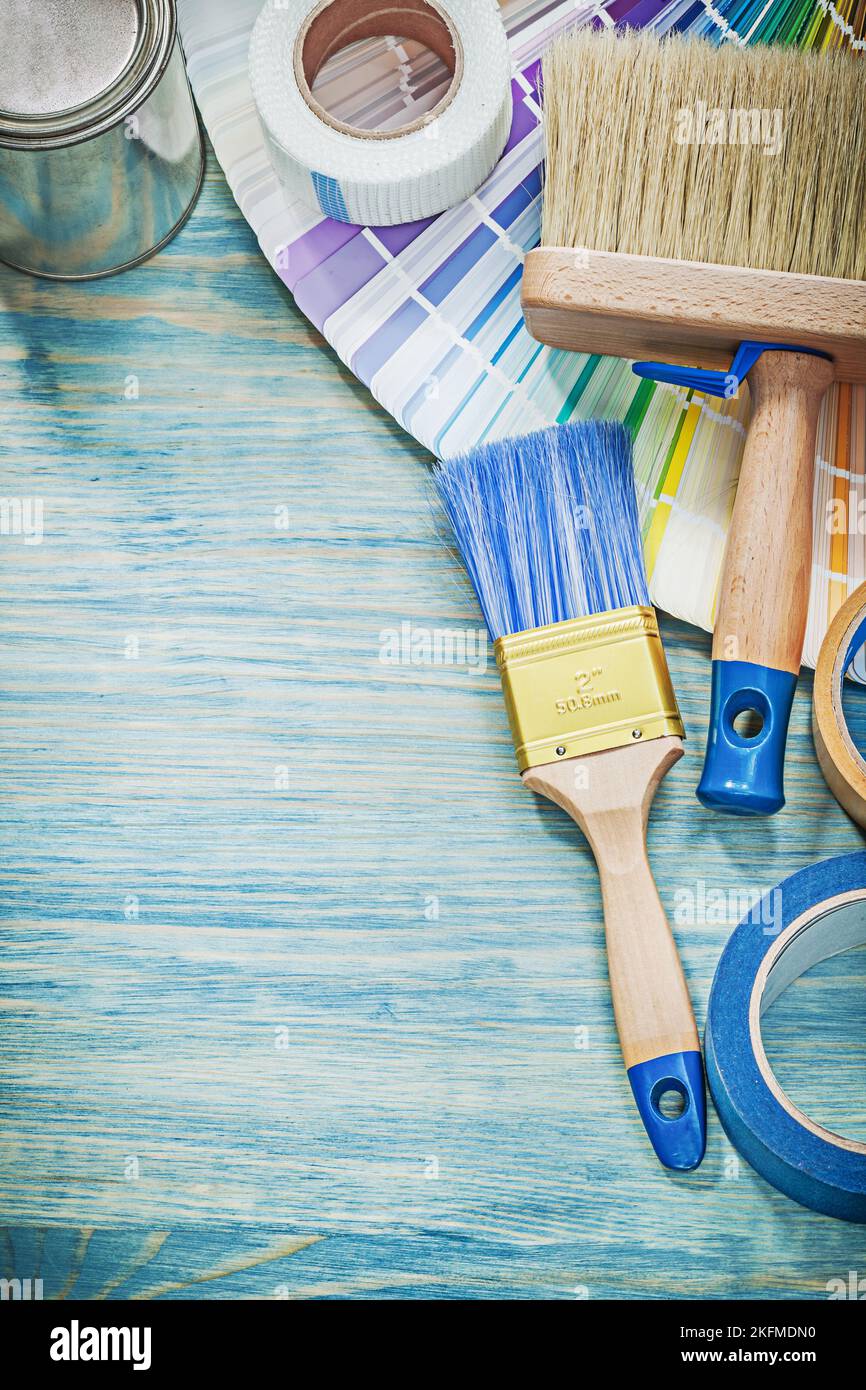 Set of paint cans brushes color sampler adhesive tape on wooden board ...
